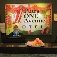 Um balcão de receção no Putra ONE Avenue Hotel com uma placa exibindo o nome do hotel.