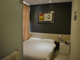 Quarto de hotel com cama, mesa de cabeceira e um quadro na parede.