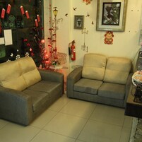 Uma sala de estar com dois sofás, uma mesinha com um vaso e uma parede decorativa com um quadro e um extintor de incêndio.
