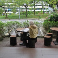Uma pessoa sentada à mesa com vista para a rua e edifícios.