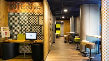 Um interior moderno com balcão de recepção, computador e banquetas de bar.