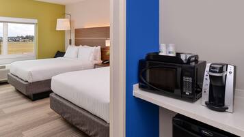 Quarto de hotel com duas camas, micro-ondas, cafeteira e vista para um campo pela janela.