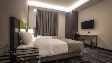 Quarto de hotel com cama, escrivaninha, cadeira, televisão e janela com cortinas.
