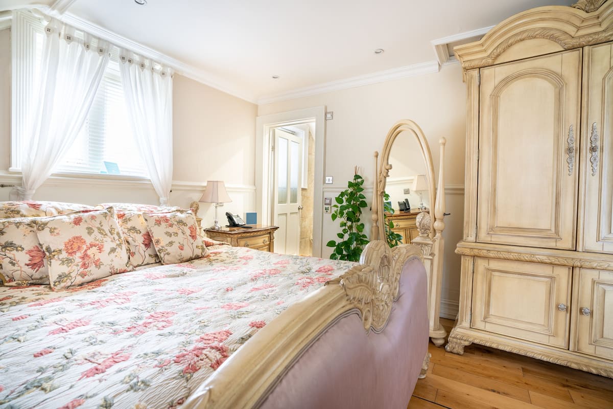 Quarto com colcha estampada, um espelho grande e um guarda-roupa.