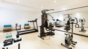 Centro de fitness com equipamentos de ginástica, esteira e espelho.
