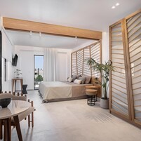 Quarto moderno com cama, mesas de cabeceira, janela e vista para o exterior.