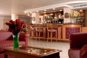 Uma área de bar com balcão, banquetas e diversos tipos de garrafas.