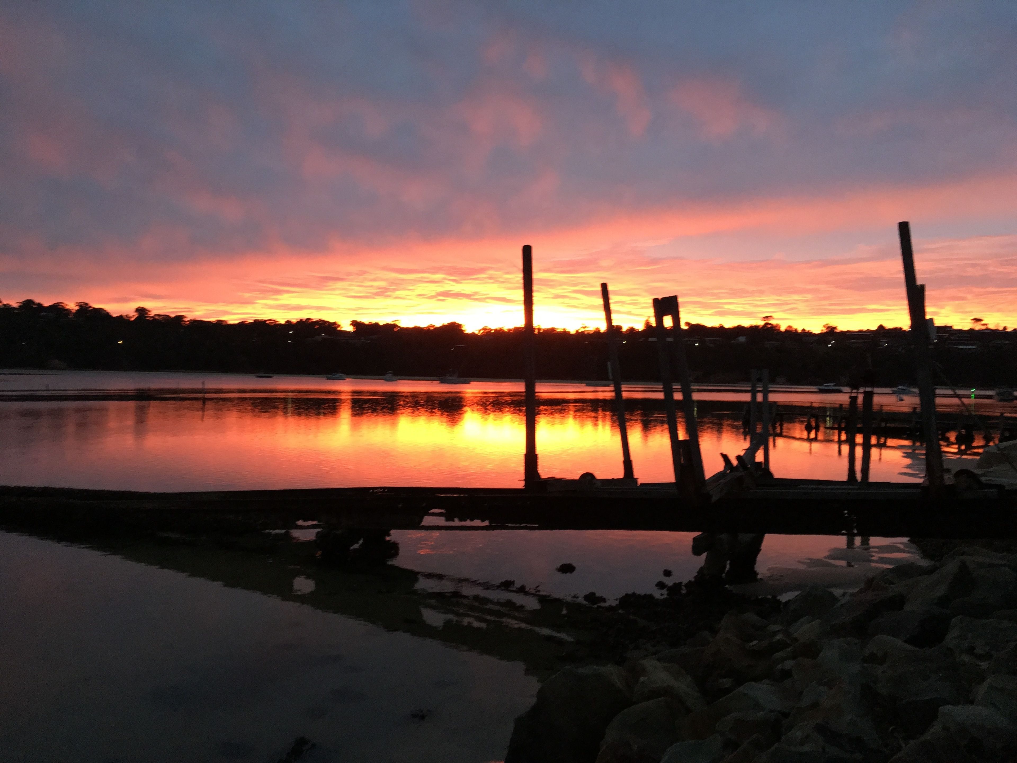 Um pôr do sol sobre um lago calmo, com um cais e barcos.