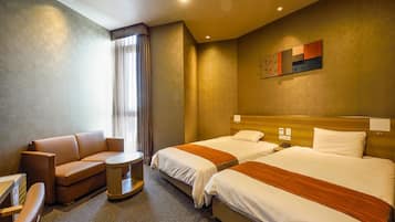 Quarto de hotel com duas camas, um sofá, uma mesinha e uma janela com cortinas.