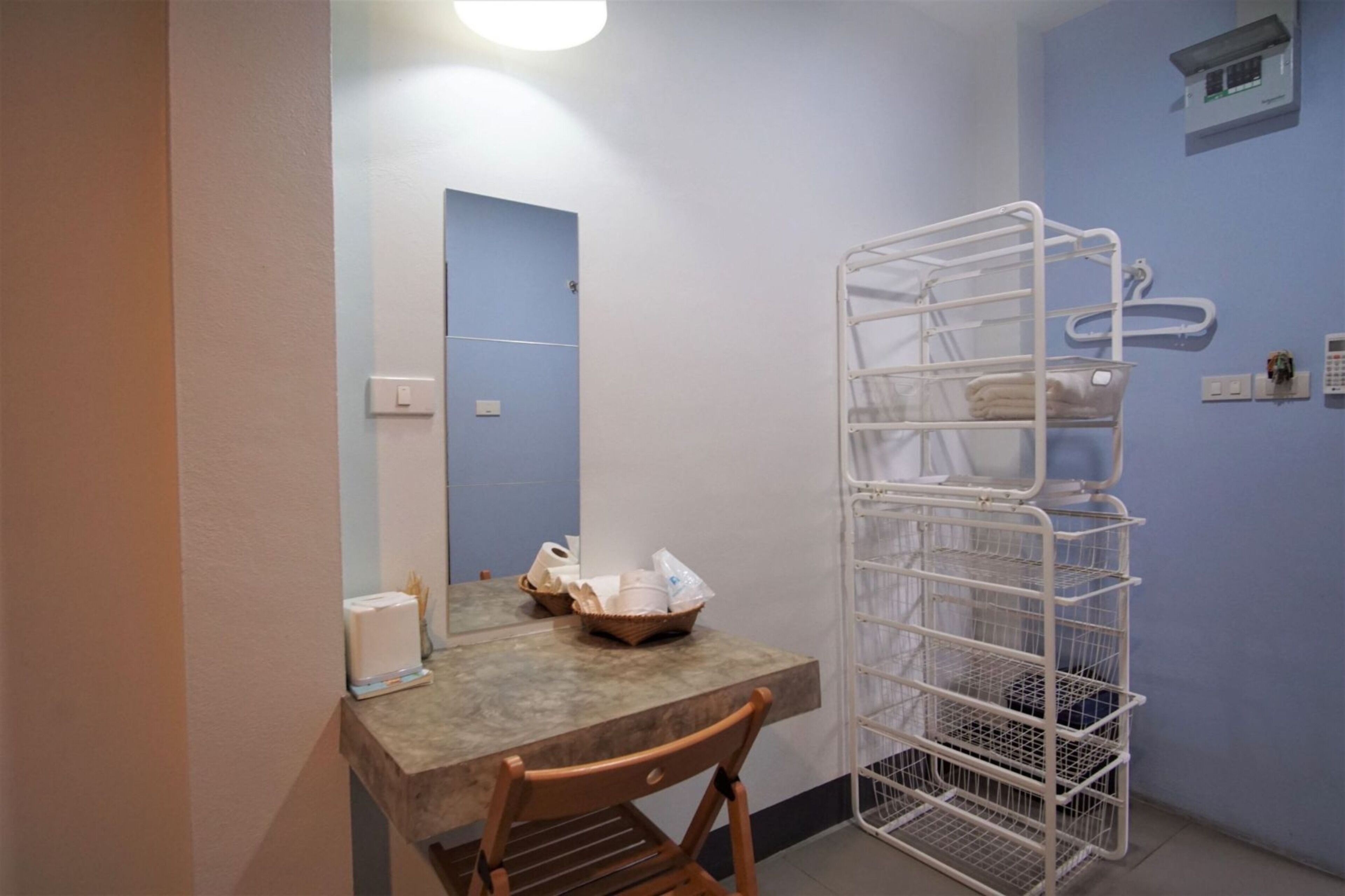Casa de banho com lavatório, espelho, porta-toalhas e uma mesa com cestos de produtos de higiene pessoal.