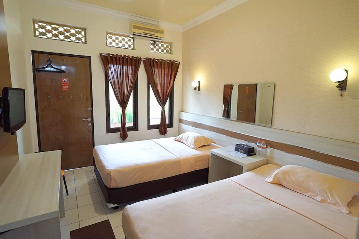 Quarto de hotel com duas camas, uma escrivaninha, uma cadeira, uma televisão e uma janela com cortinas.