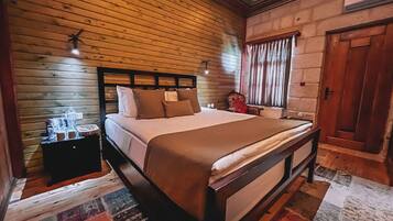 Quarto com painéis de madeira, cama, mesas de cabeceira e uma janela com cortinas.