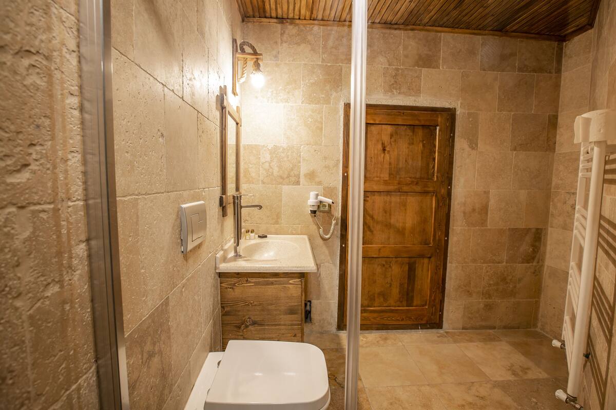 Uma casa de banho com porta de madeira, uma pia e uma sanita.