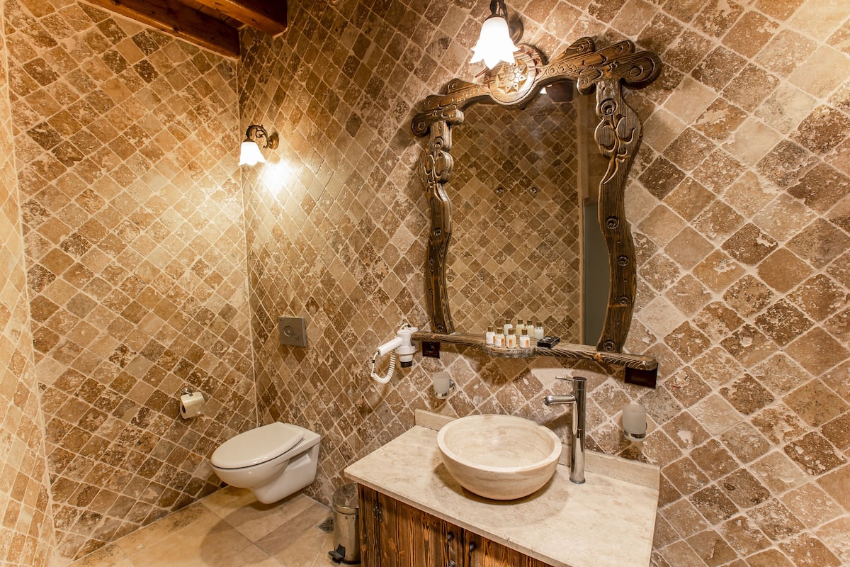 Casa de banho com um espelho grande, lavatório e sanita.