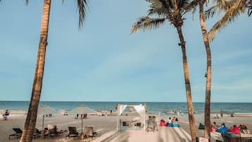 Na praia, areia branca, guarda-sóis, bar na praia