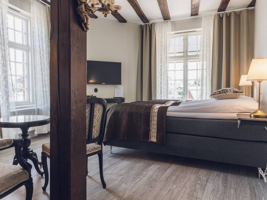 Quarto de hotel com cama, televisão, mesa e cadeira.