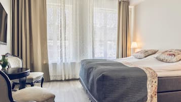 Quarto de hotel com cama, cadeira, mesa e abajur.