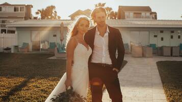 Um casal a rigor de casamento posado num pátio com um edifício ao fundo.