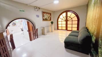 Um saguão com balcão de recepção, escada e uma grande janela em arco.