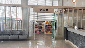 Um hall de entrada com balcão de recepção, área de estar e uma loja com prateleiras repletas de produtos.
