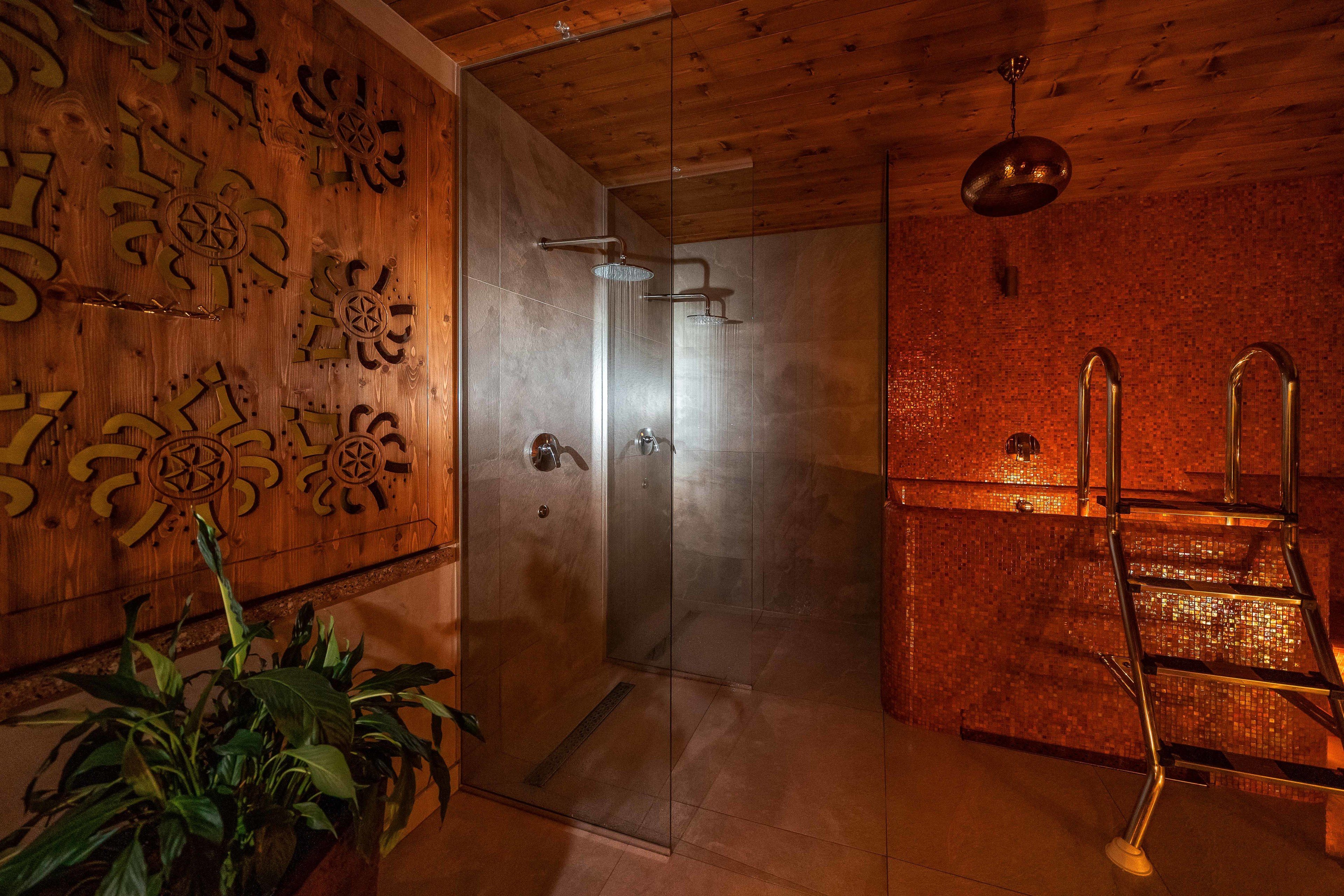 Interior de madeira com chuveiro, porta de vidro e escada de metal.