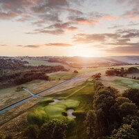Um campo de golfe com lagoa, armadilhas de areia e mastro de bandeira.