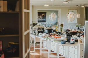 Uma área de cozinha com armários brancos, uma máquina de café e diversos utensílios.