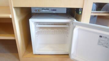 Uma geladeira compacta com tela digital, posicionada sob uma bancada de madeira em uma cozinha.