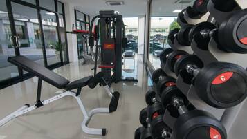 Uma academia com equipamentos de ginástica, incluindo um banco e uma barra com halteres.