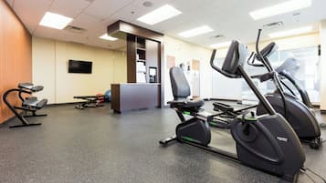 Uma academia com esteiras, um banco de musculação e uma mesa de recepção.