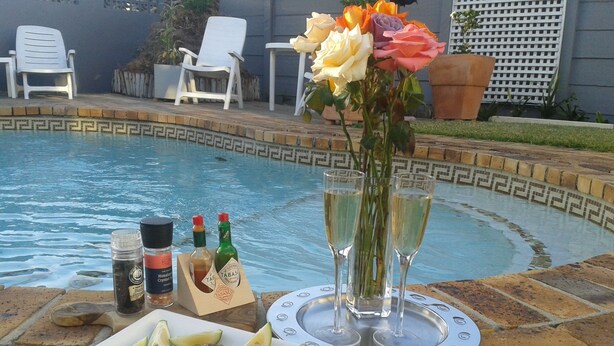Mesa à beira da piscina com ostras, fatias de limão e duas garrafas de molho Tabasco.