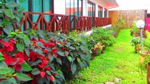 Um hotel com jardim murado, vasos de plantas e gramado bem cuidado.
