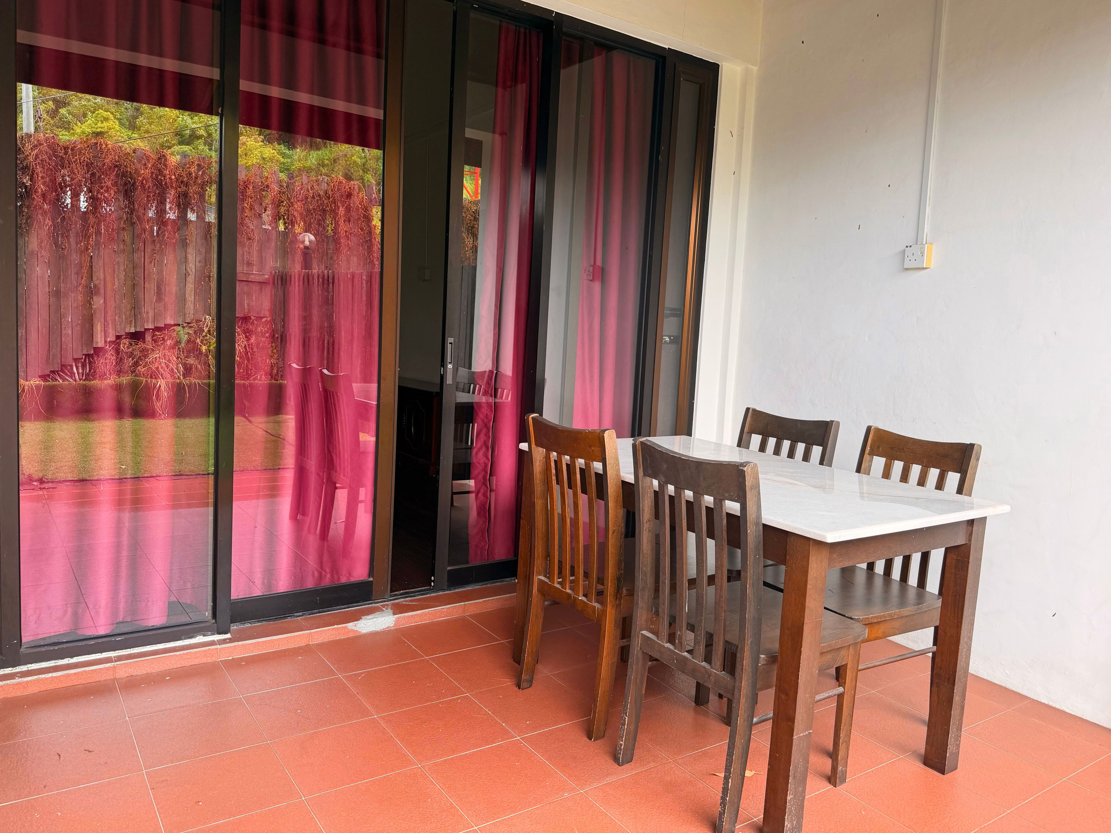 Uma área de refeições com mesa e cadeiras, uma porta de vidro deslizante com cortinas e piso ladrilhado.