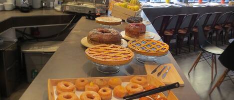 Buffet com diversos pastéis e uma máquina de café.