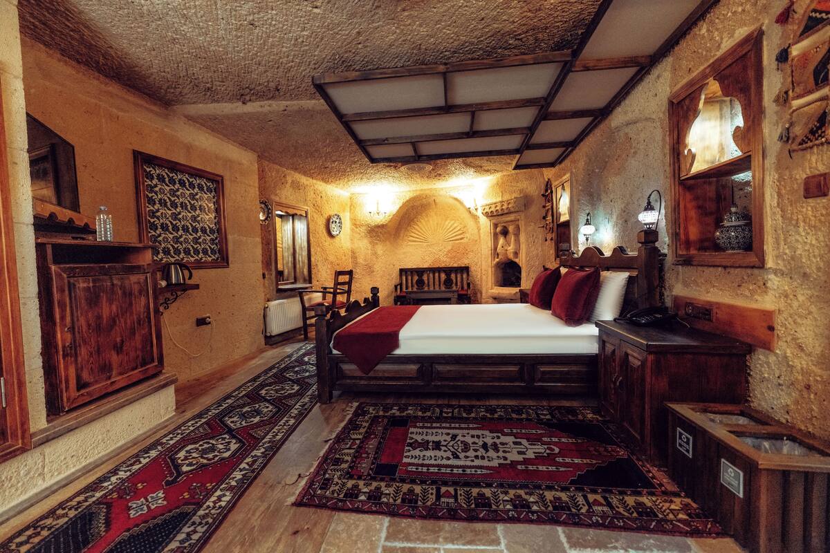 Quarto tradicional com cama, móveis de madeira e um tapete estampado.