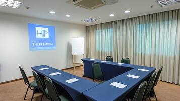 Uma sala de conferências com uma mesa comprida, cadeiras, tela de projetor e um quadro branco.