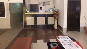 Uma área de recepção com balcão, recepcionista, relógio e porta.