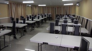 Uma sala de conferências com várias mesas e cadeiras, dispostas em fileiras.