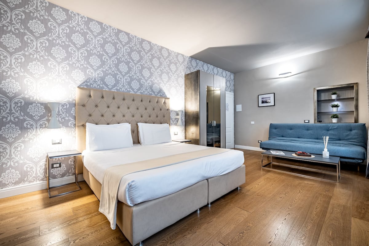 Um quarto moderno com uma cama grande, um sofá azul e piso de madeira.