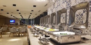 Disposição de buffet com várias estações de serviço, um balcão com televisão e azulejos com padrão.