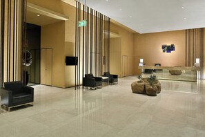 Um lobby moderno com balcão de recepção, área de estar e um arranjo floral decorativo.
