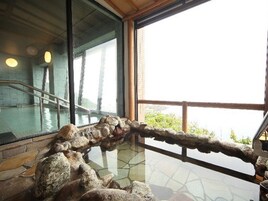 Mural de pedra com corrimão de madeira com vista para uma área de piscina.