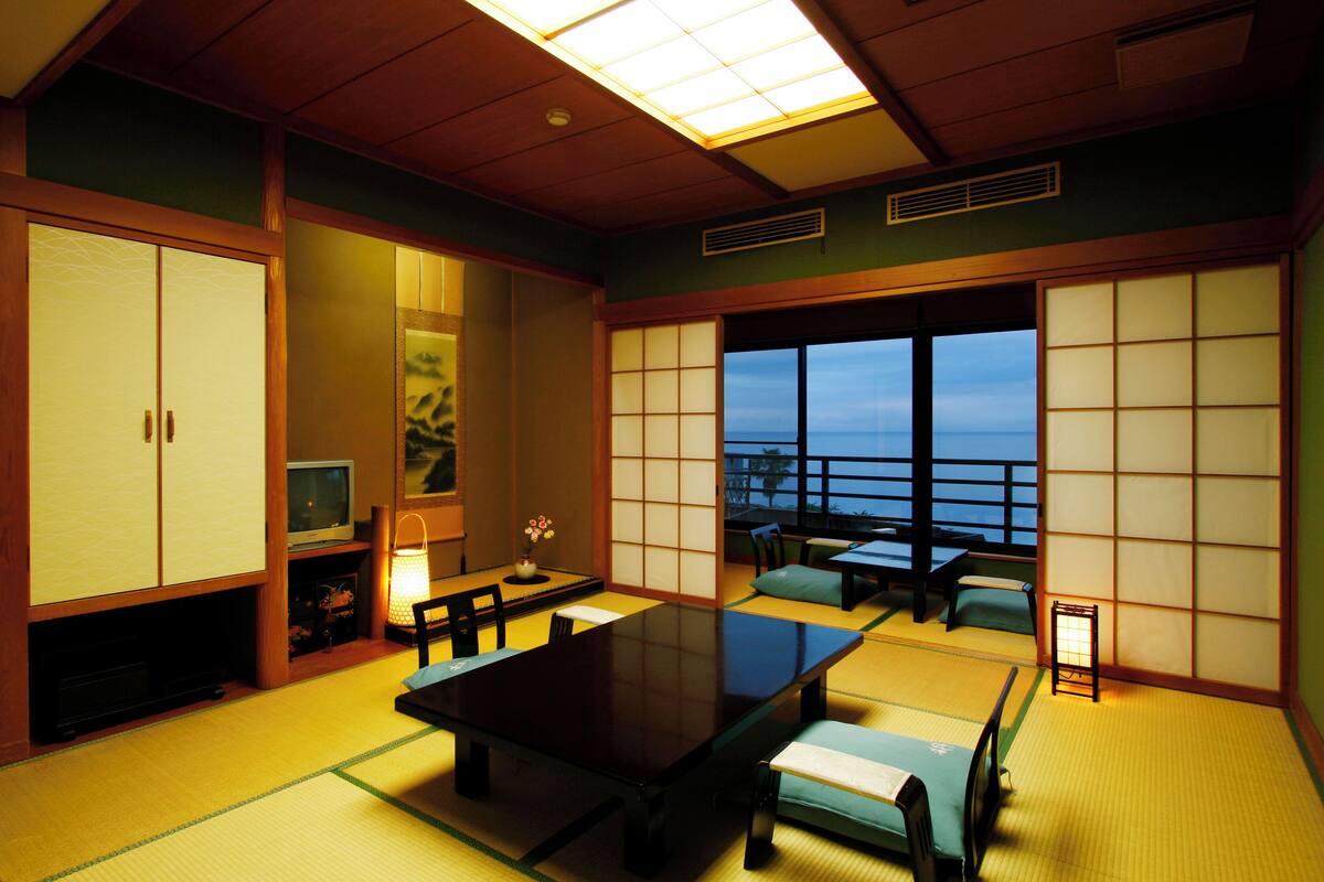 Um quarto em estilo tradicional japonês, com piso de tatame, uma mesa baixa e portas deslizantes.