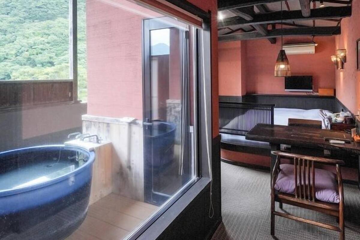 Quarto com janela grande, banheira de hidromassagem, cama e área de jantar.