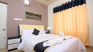 Uma cama bem arrumada com roupa de cama branca e detalhes escuros, uma mesa de cabeceira com abajur, uma luminária na parede e um quadro sobre a cama.