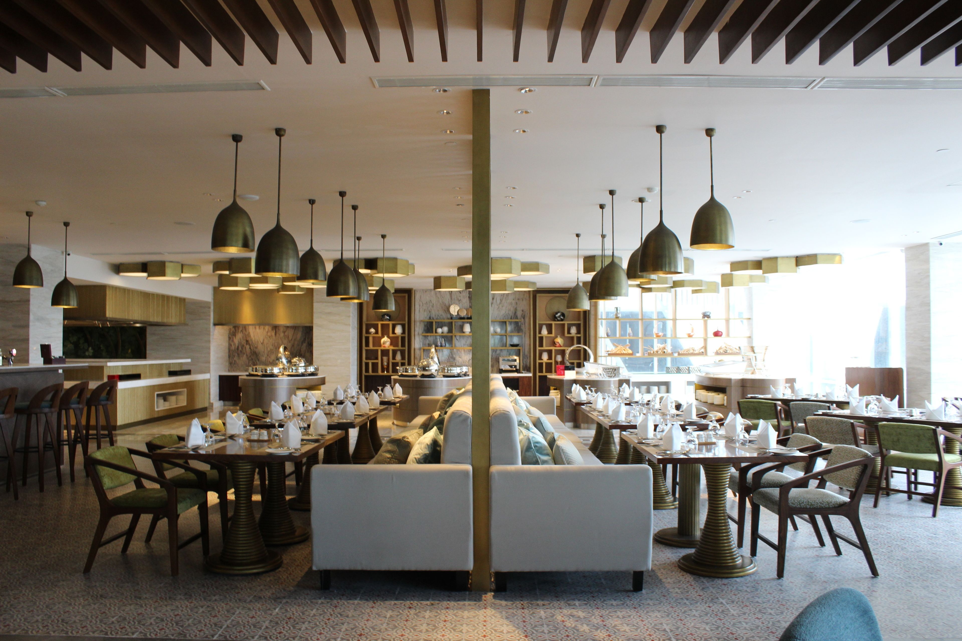 Um restaurante moderno com área de estar central, diversas mesas de jantar e luminárias pendentes.