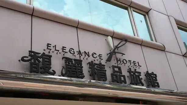 Placa de hotel com o nome 'Elegance Hotel' e caracteres chineses.