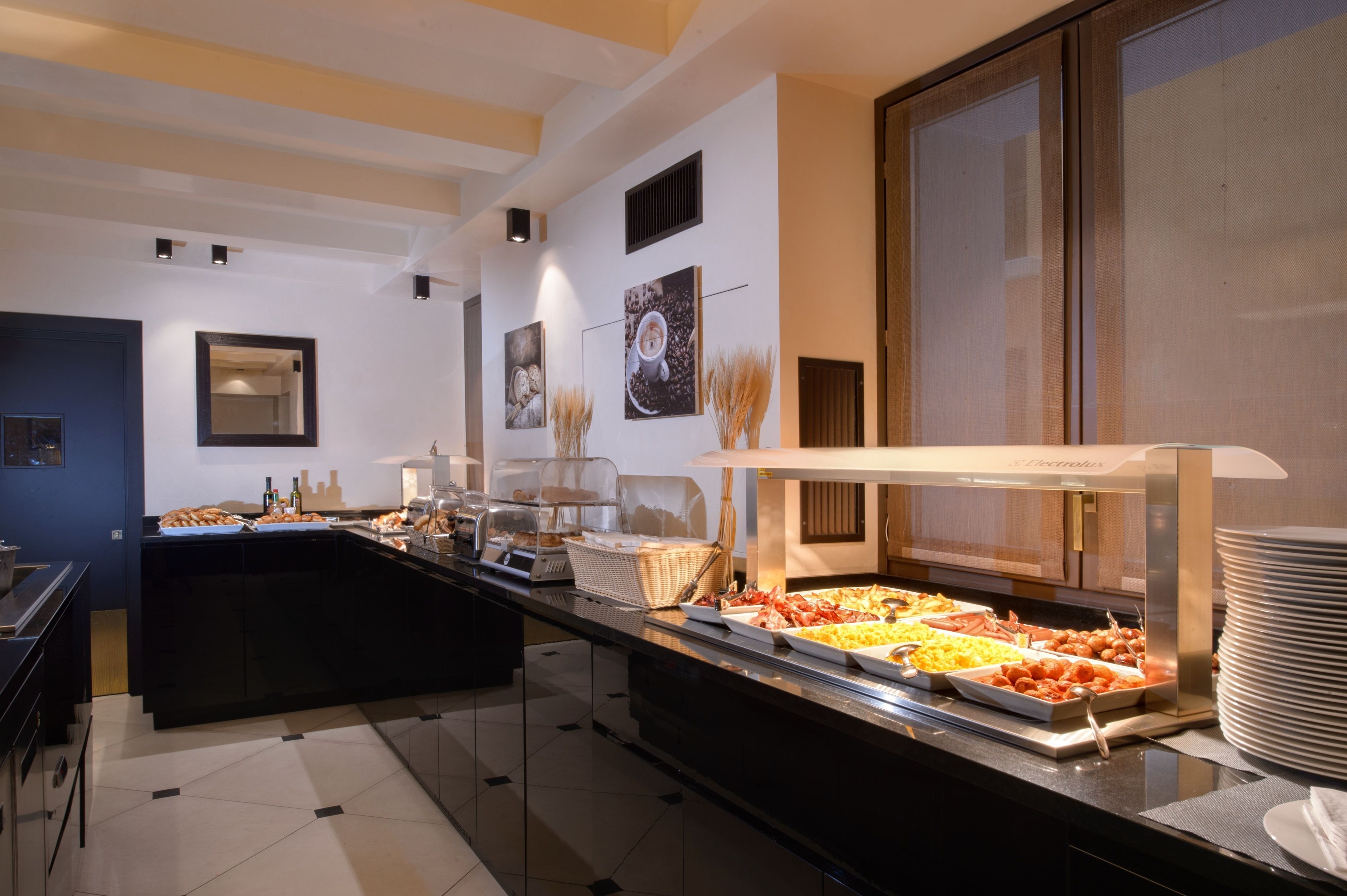 Uma área de buffet com diversos alimentos, um canto de café e um espelho na parede.