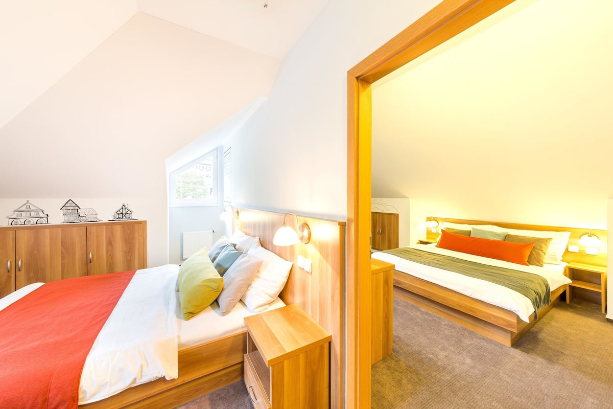 Quarto com cama, mesa de cabeceira, guarda-roupa de madeira e espelho.