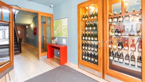 Um hall de hotel com escadaria, balcão de recepção e armários para exibição de vinhos.